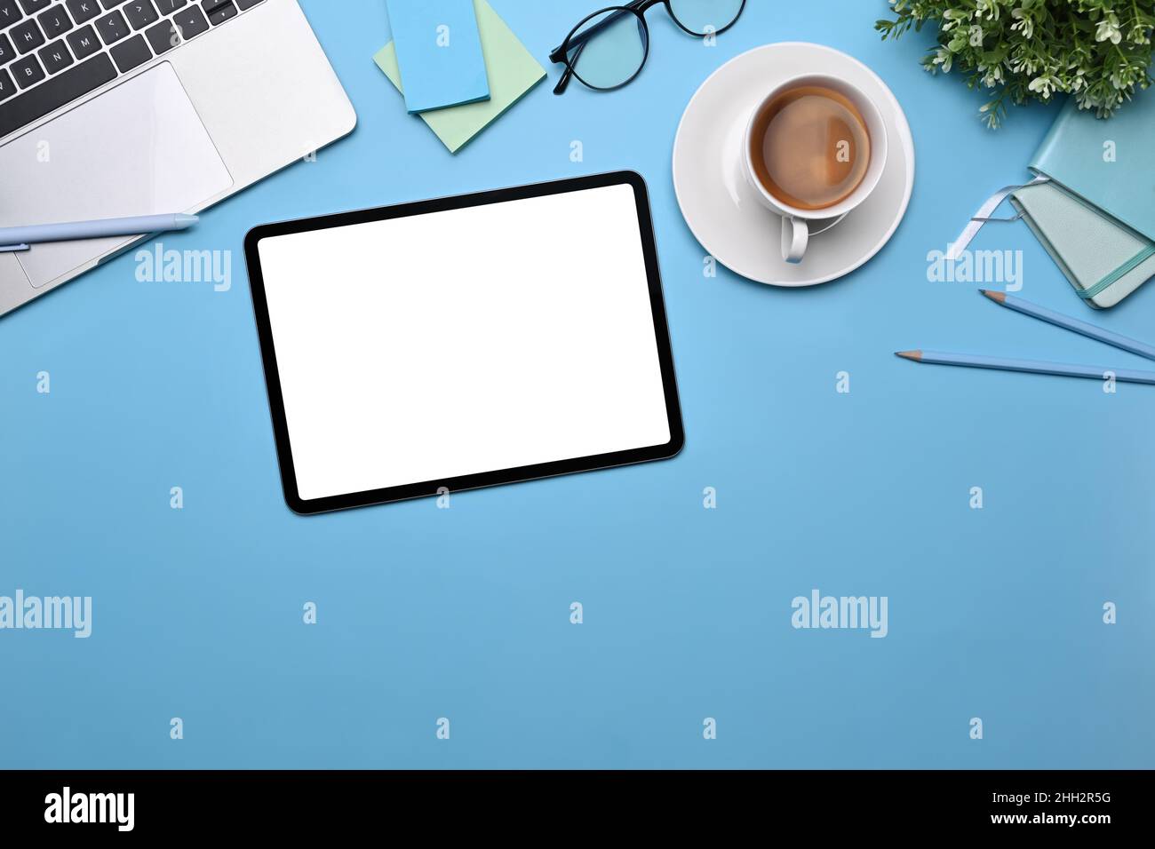 Top view digital tablet, coffee cup, sticky notes and laptop on blue ...