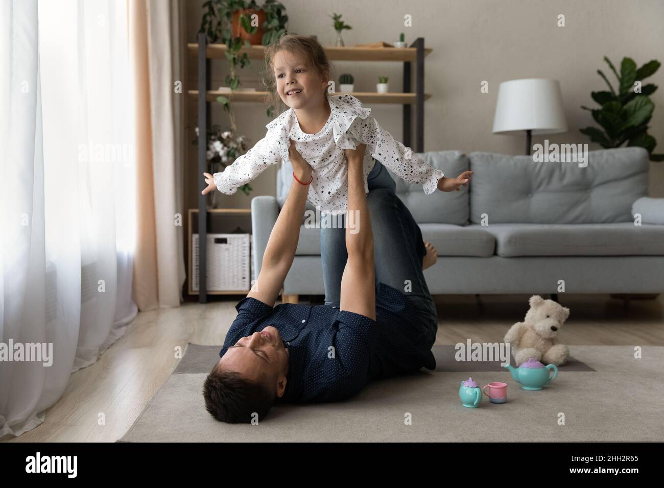 Happy young dad lifting in air small daughter Stock Photo - Alamy