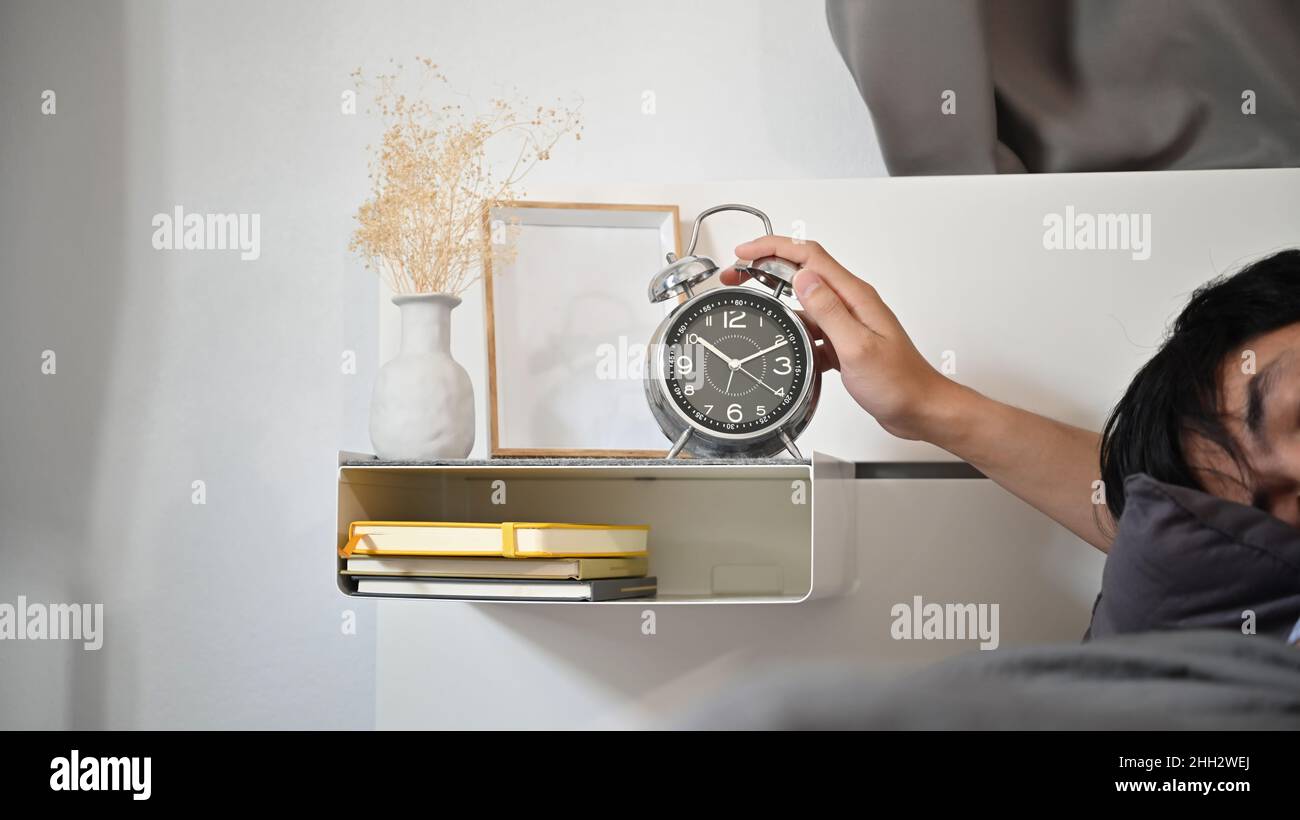 Man Lying In Bed And Hand Reaching To Turn Off Alarm Clock Switch Stock