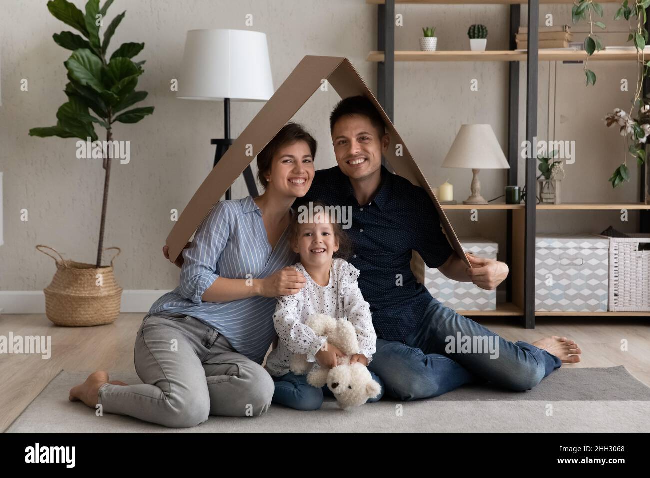 Loving parents and small kid sitting under carton roof Stock Photo - Alamy