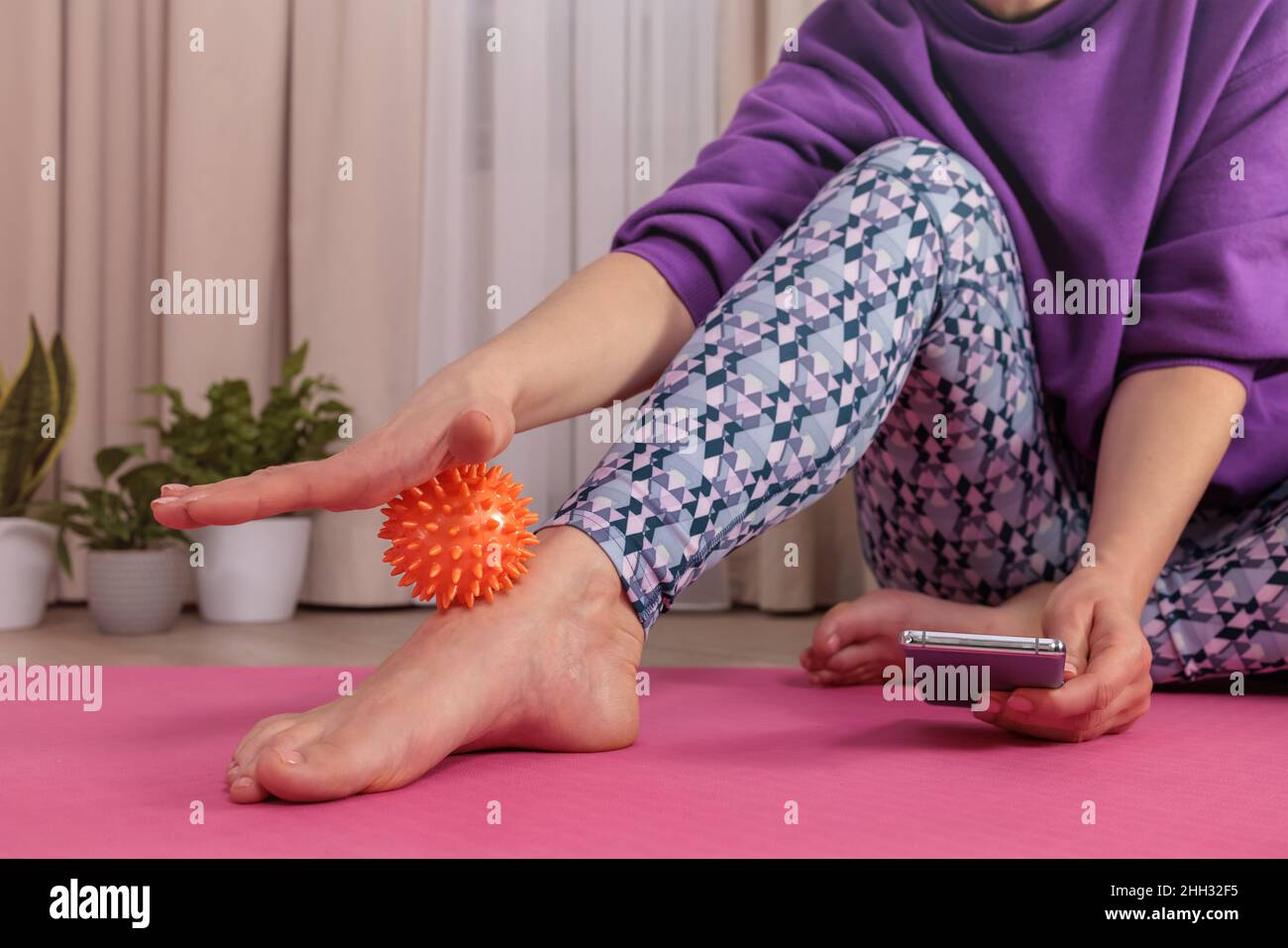 girl sits on floor and massages herself with prickly ball to relax and ...