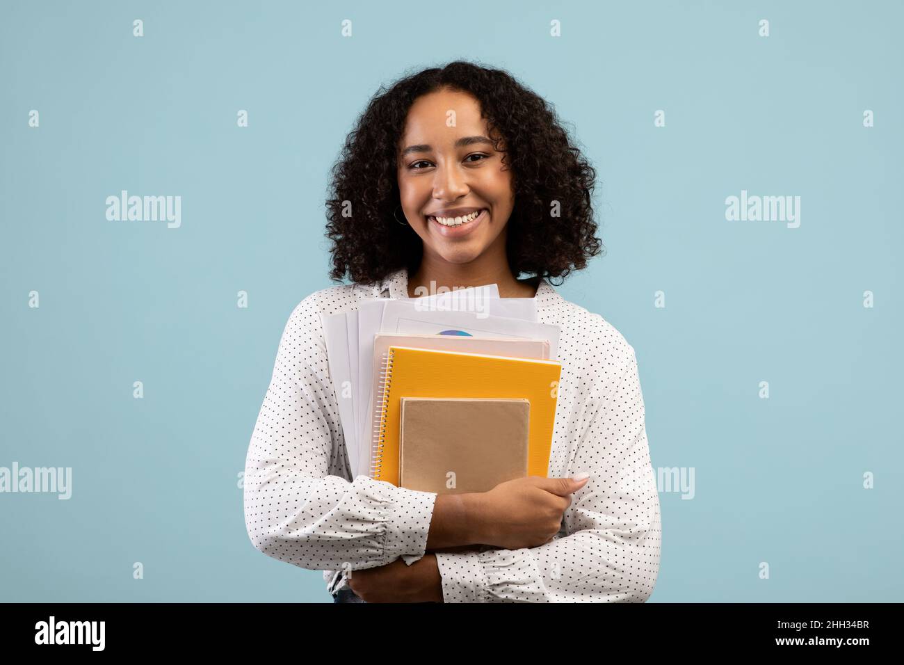 Portrait of young black female student with notebooks posing and ...