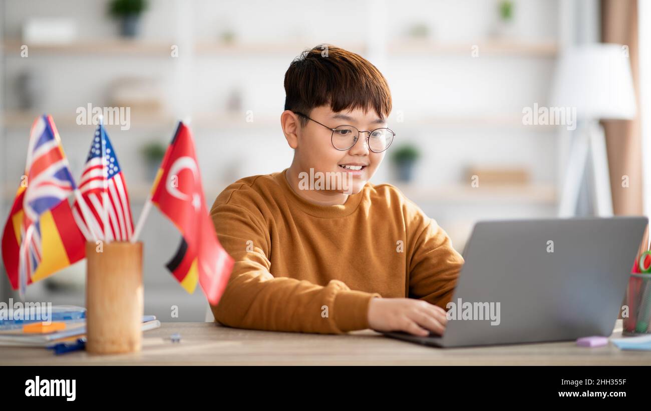 Happy chinese teenager boy using laptop, learning foreign language ...