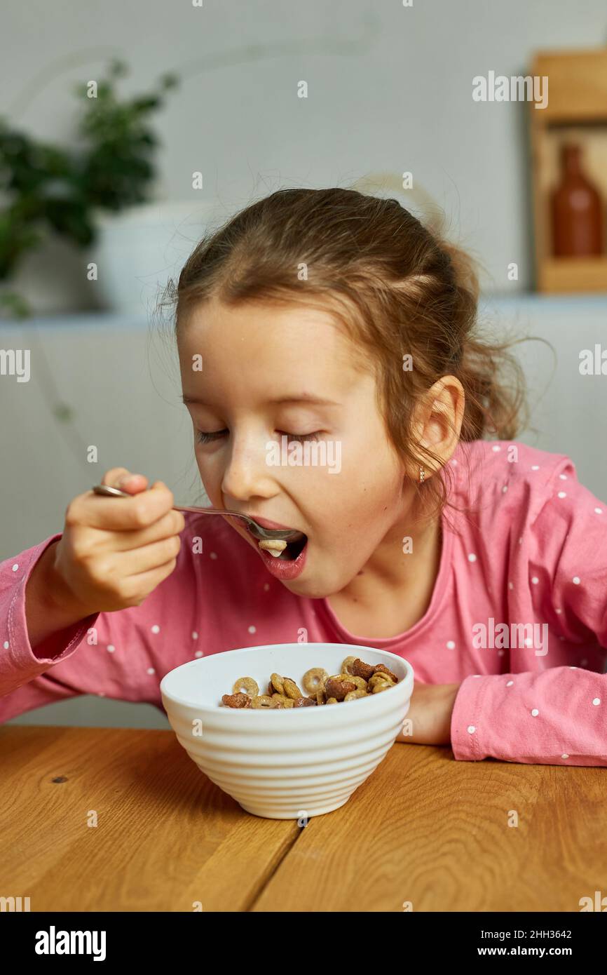 Cute little girl enjoy eating cereal with milk for morning breakfast ...