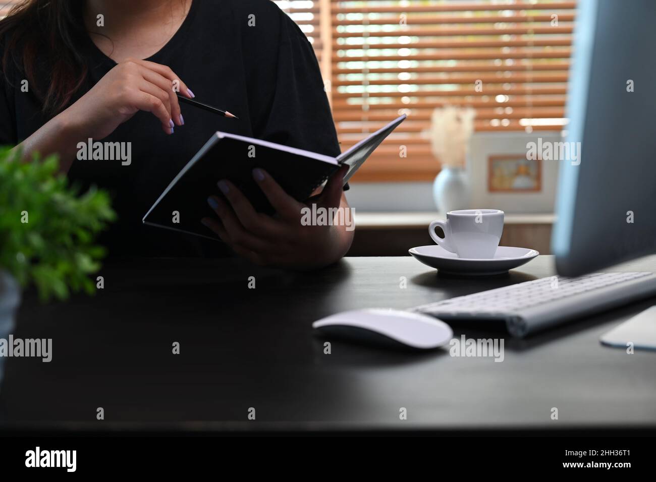 Female using computer and making notes on notebook Stock Photo - Alamy