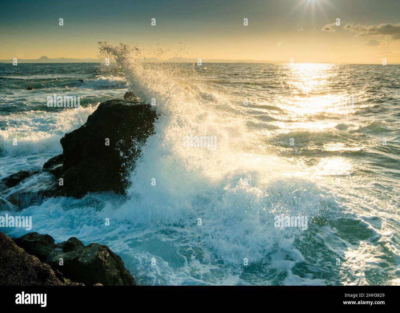 As cold, dark, winter blue ocean waves crash against the rocks, the ...