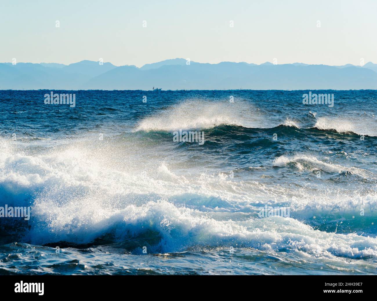 Offshore winds shred the crests of waves pounding the rocky coastline ...