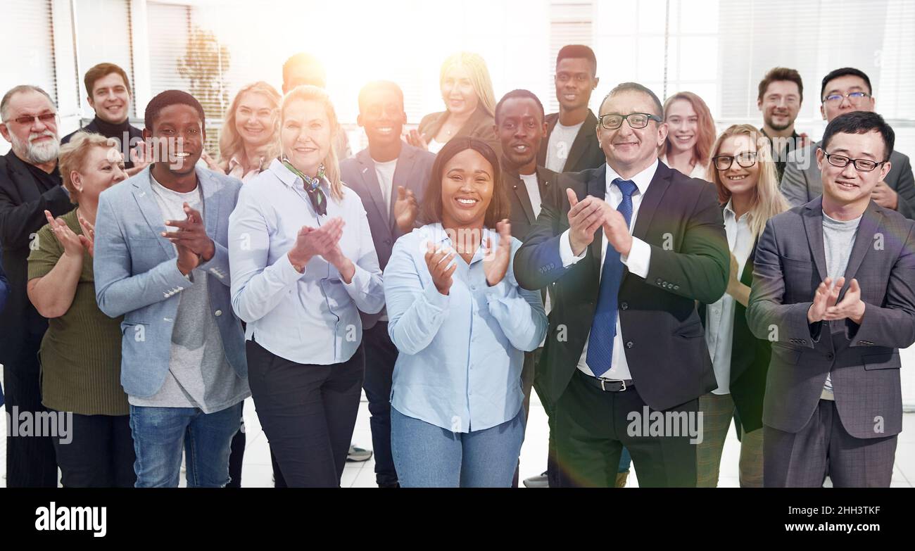 Happy group of business team clapping hands in the bright modern hall ...