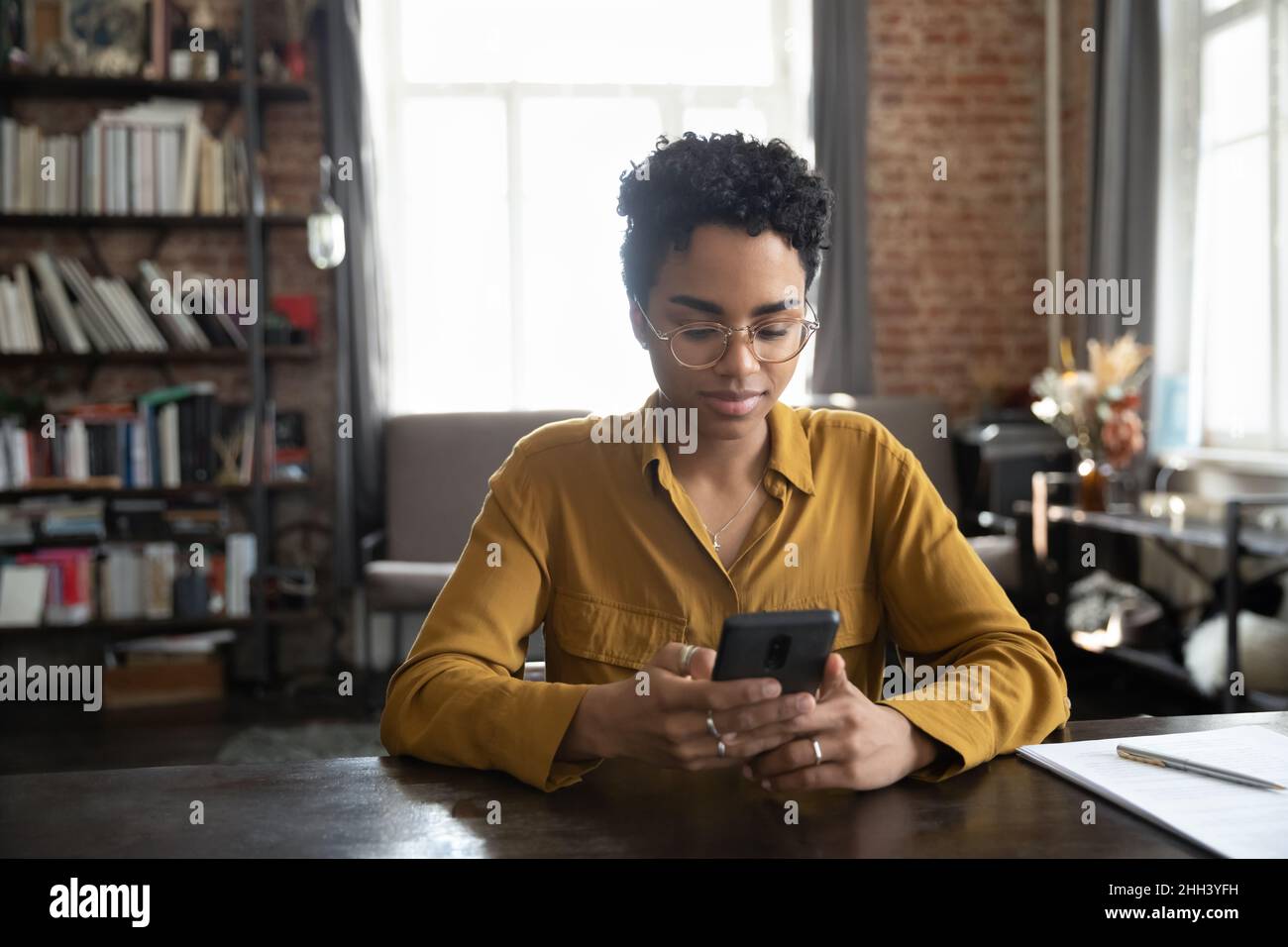 Serious Afro American business woman watching content on smartphone ...