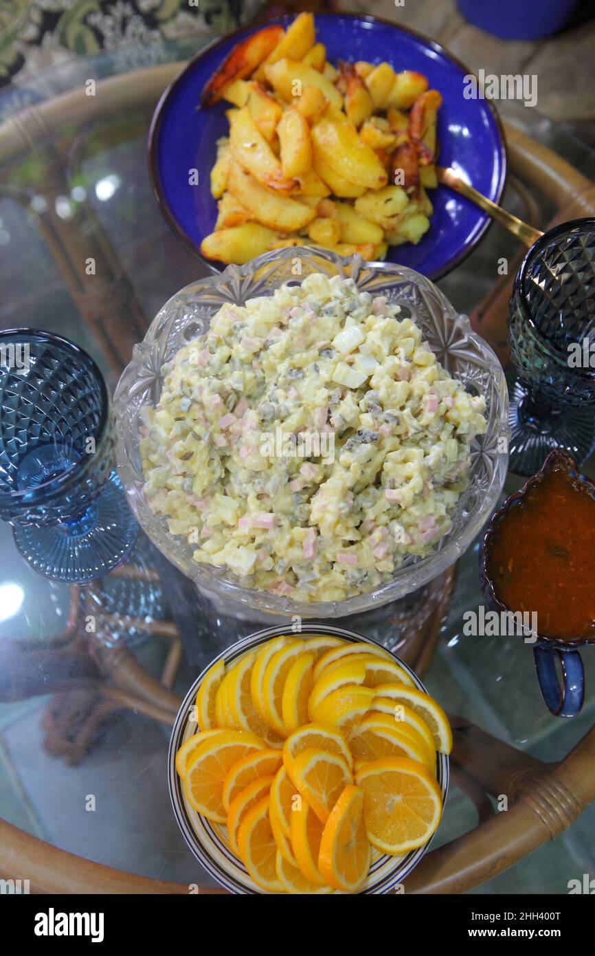 Olive salad, fried potatoes, lemons and glasses on a glass table Stock ...