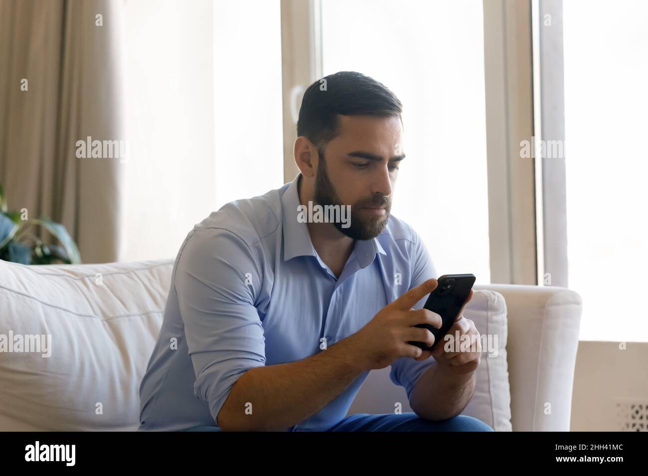 Focused millennial mobile phone user man chatting online Stock Photo ...