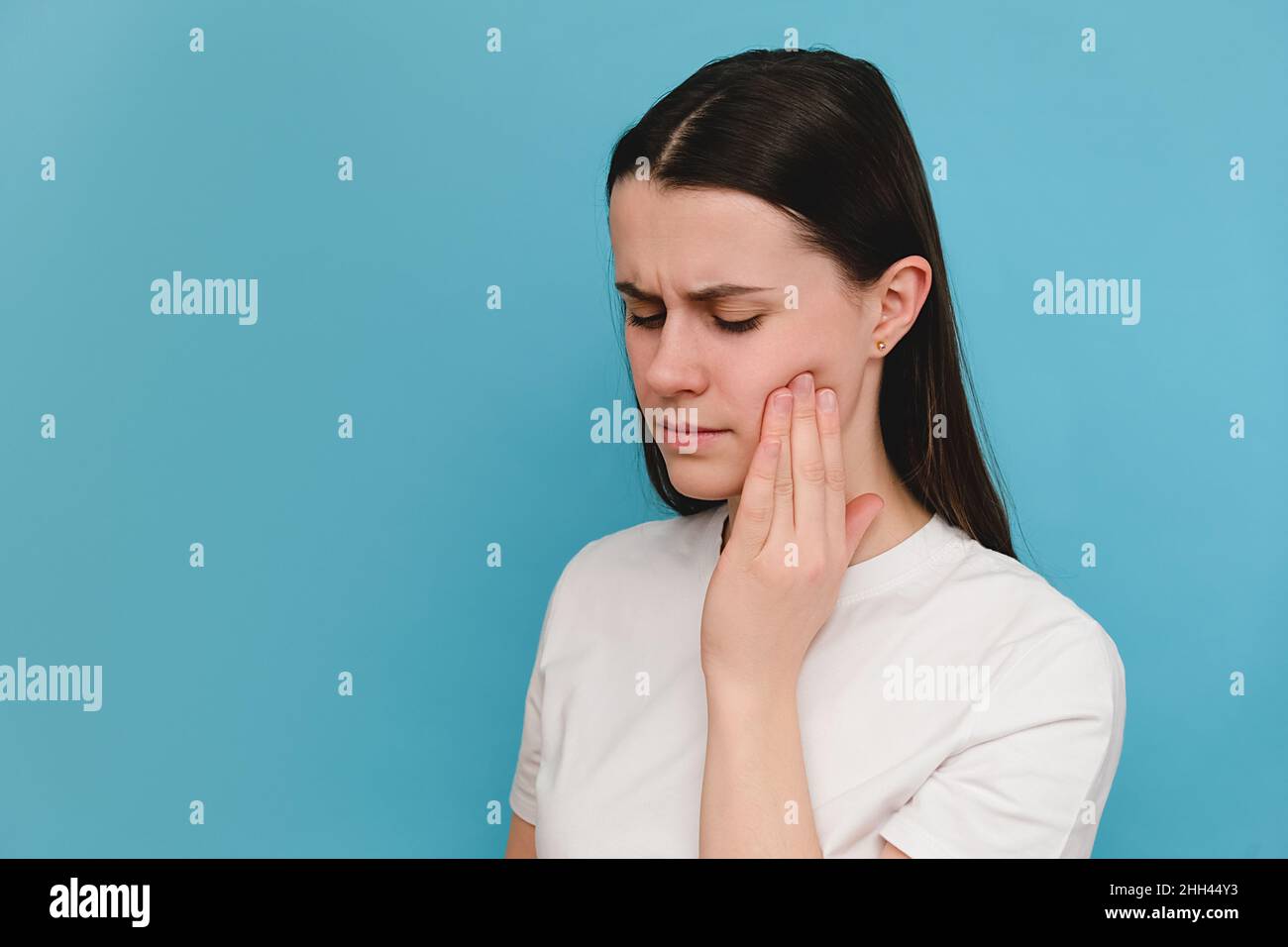 Close up of young brunette female suffering from toothache, isolated on ...