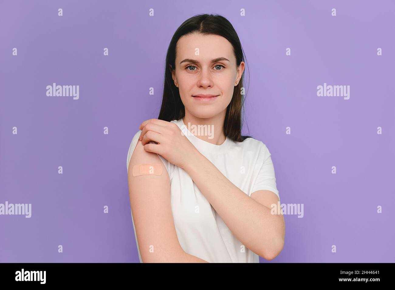 Portrait of happy vaccinated woman showing arm with plaster bandage ...