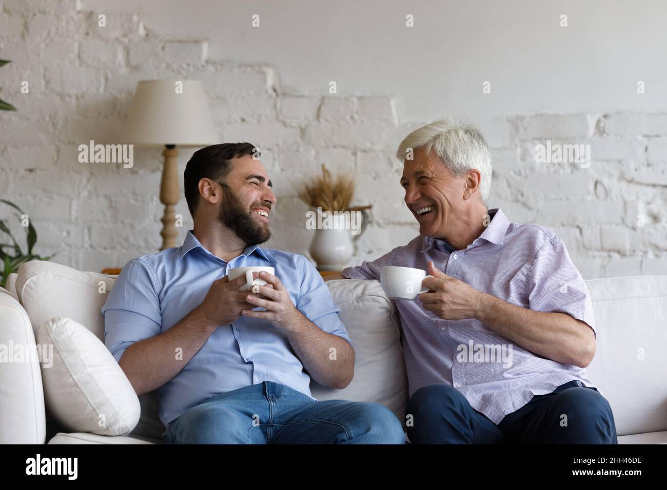 Cheerful senior 70s dad and adult grownup son drinking tea Stock Photo ...