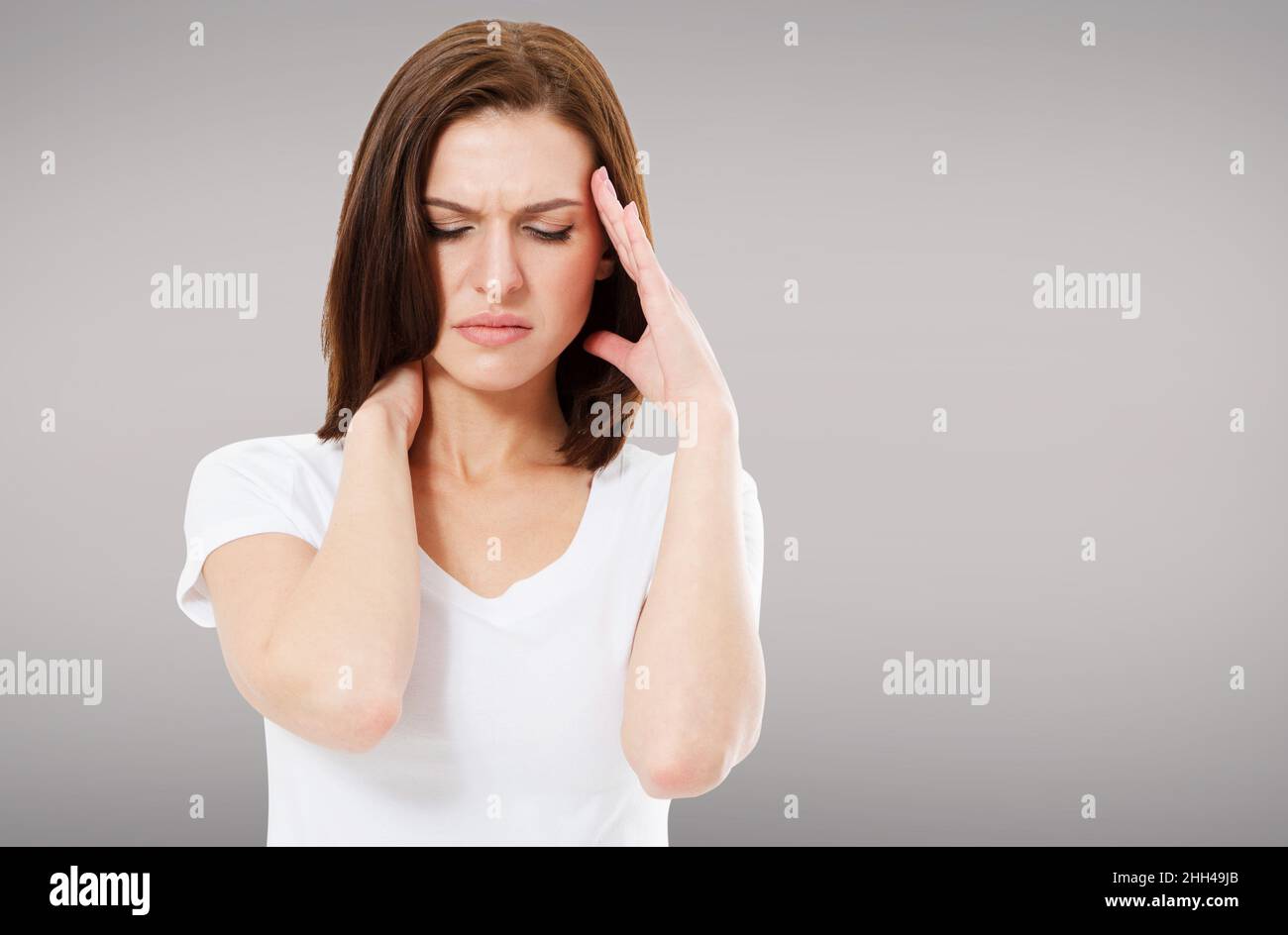 suffering brunette woman on grey background, headaches Stock Photo - Alamy