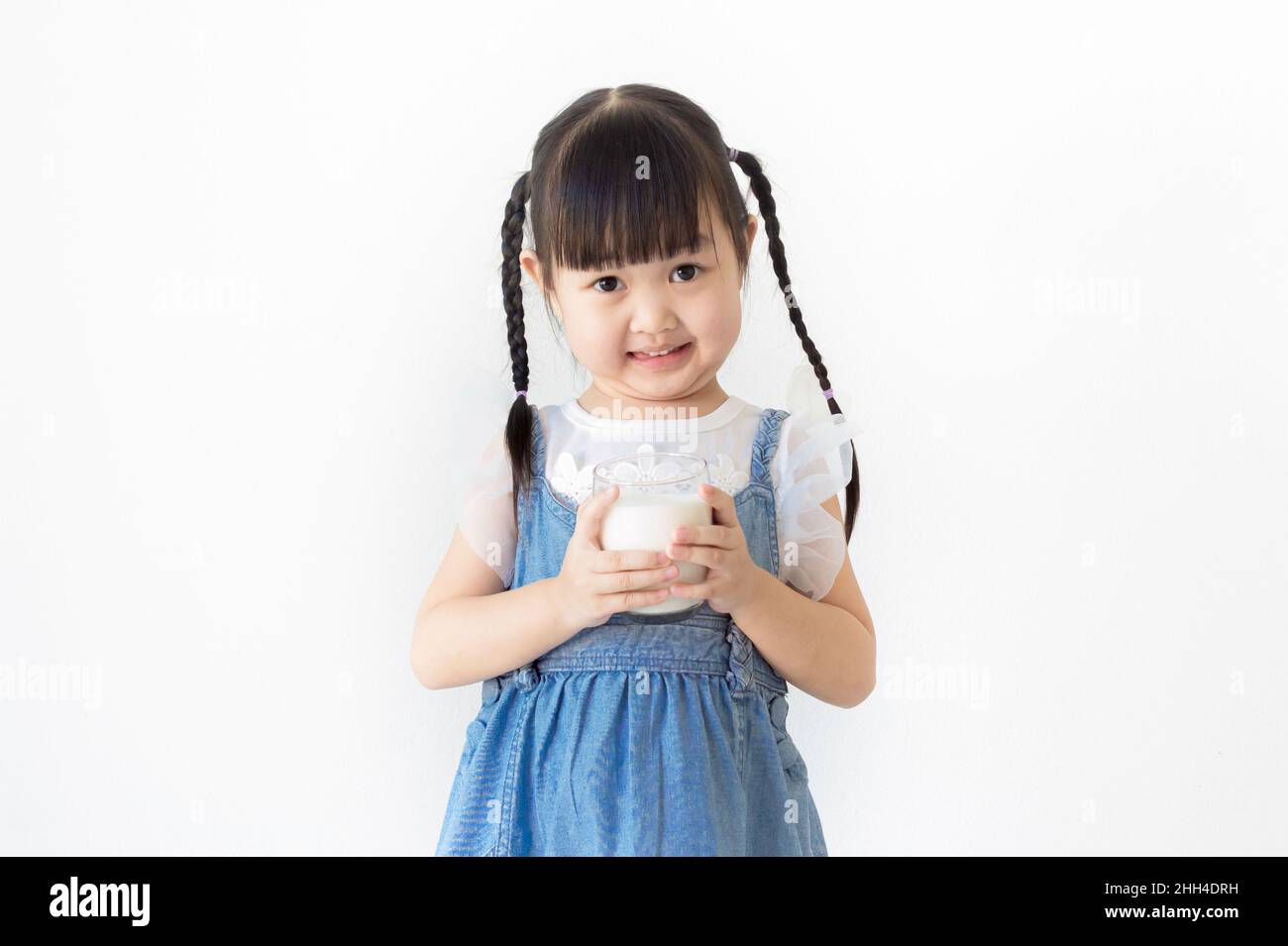 Portrait cute smiling Asian girl holding a glass of milk with white background Stock Photo - Alamy