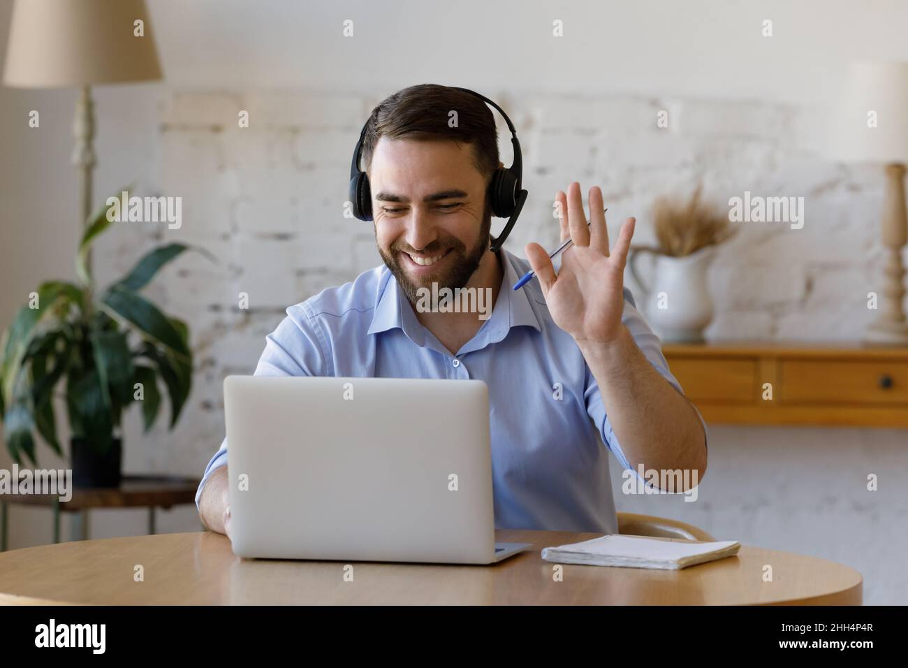 Happy friendly support employee in headphones talking on video call ...