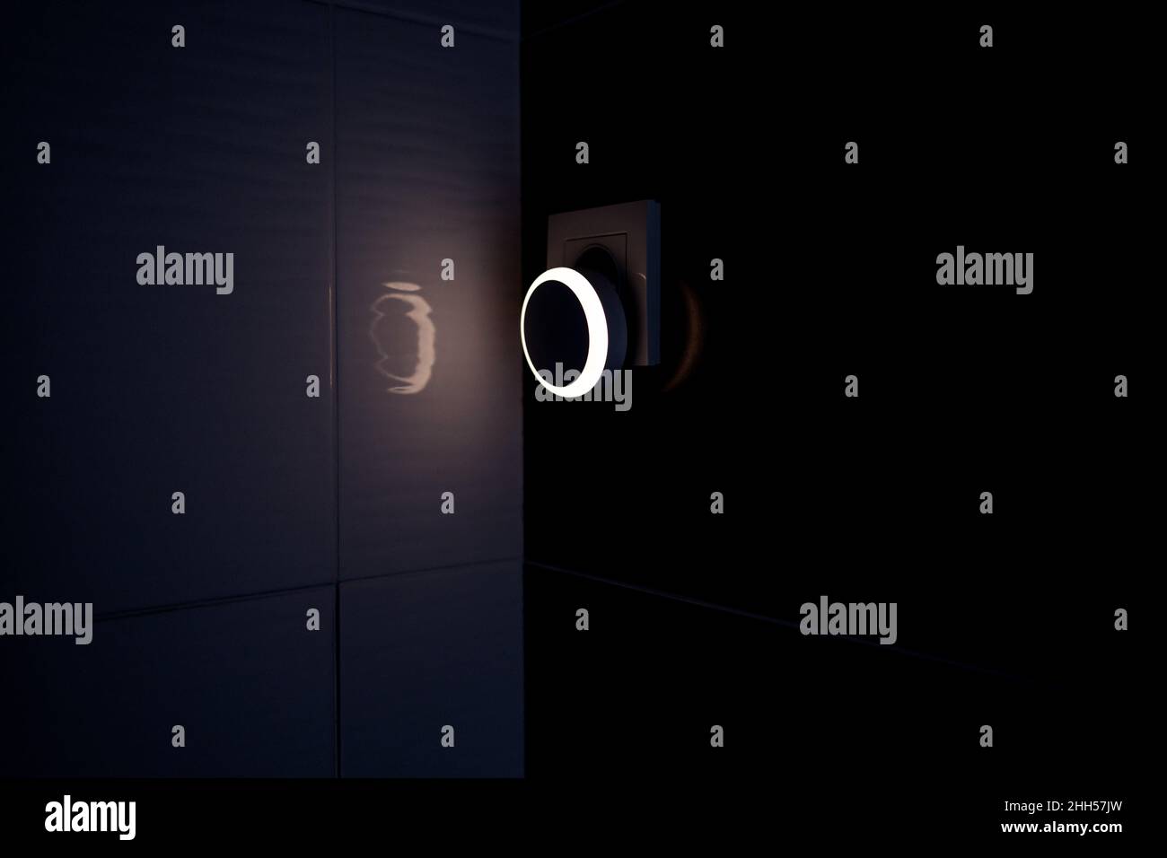 Cold light from the bulb in plug . Concept Night light in the dark ...