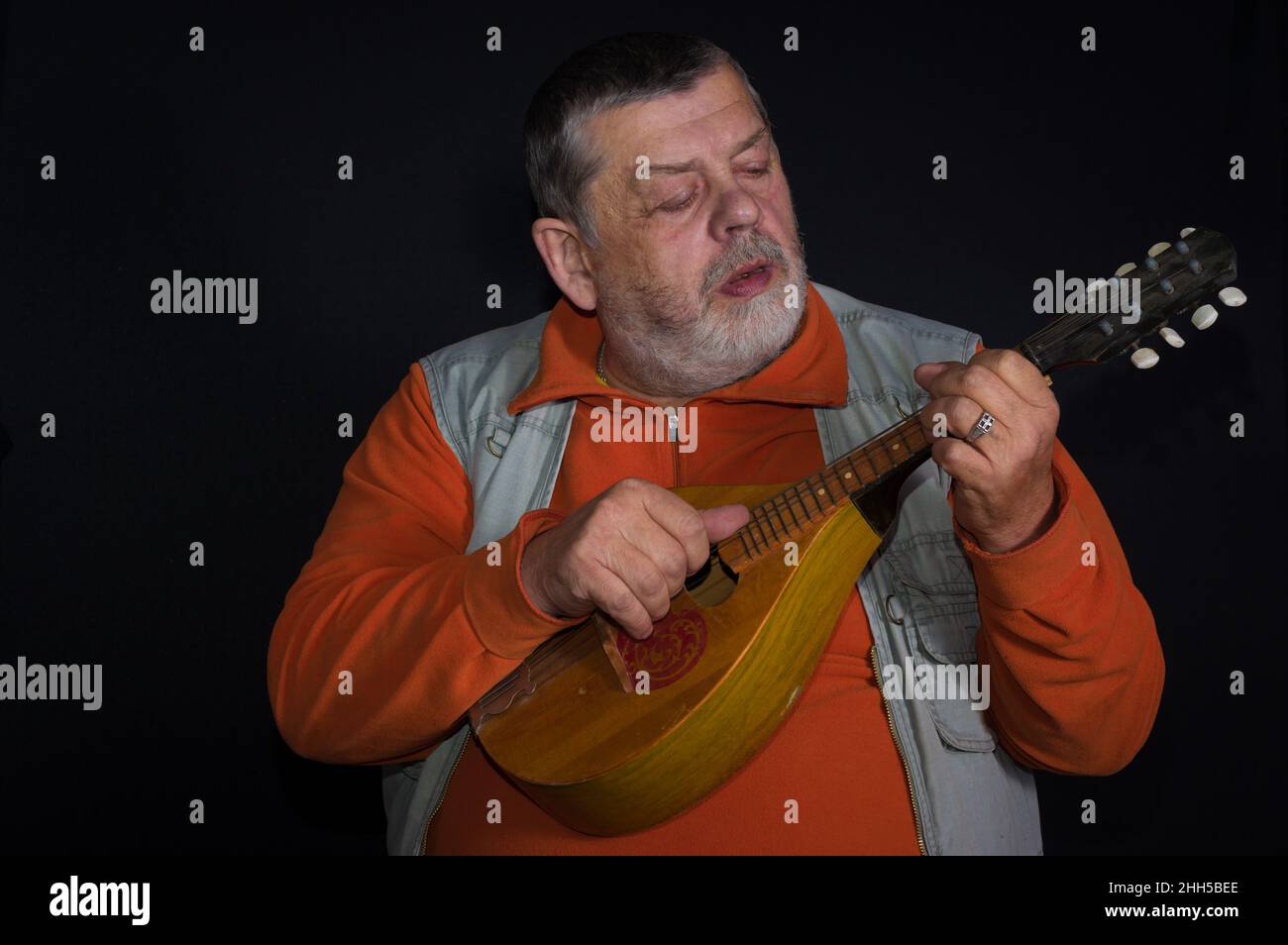 Nice low key portrait of Caucasian senior musician playing mandolin ...