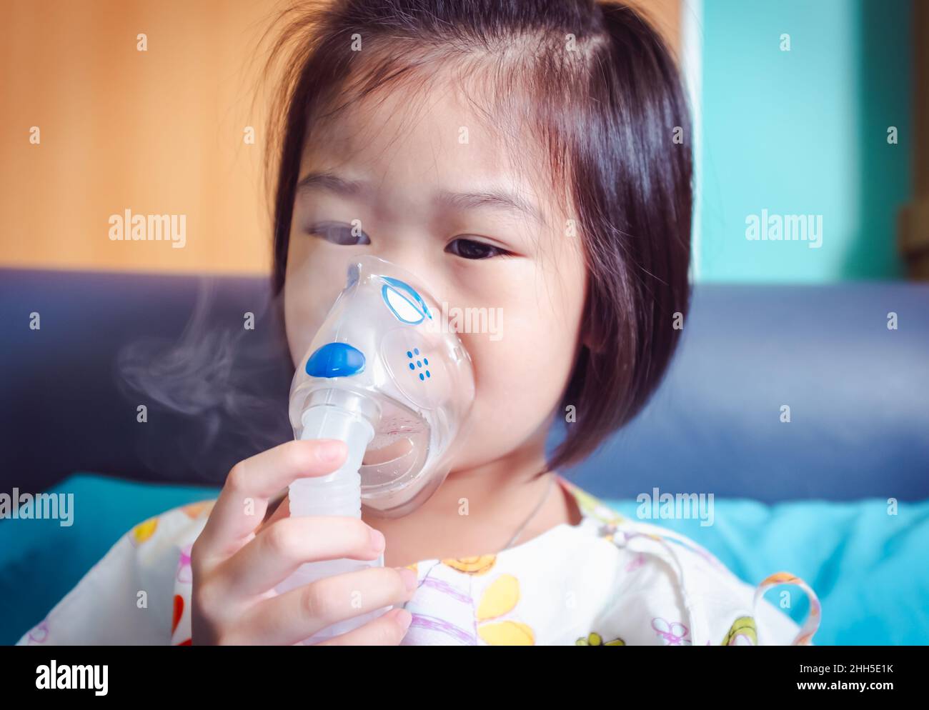 Sad asian child holds a mask vapor inhaler for treatment of asthma ...
