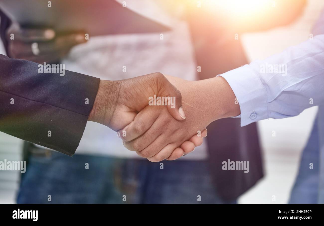 Closeup of handshake of business partners on background of employee in ...