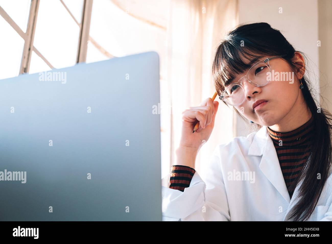 Young chemist thinking while looking at laptop in laboratory Stock ...