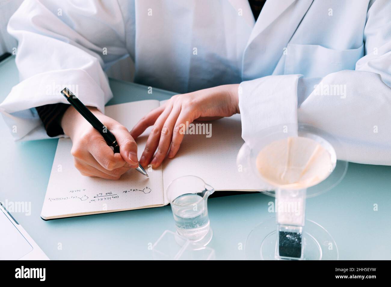 Young scientist writing chemical formula on book in laboratory Stock ...