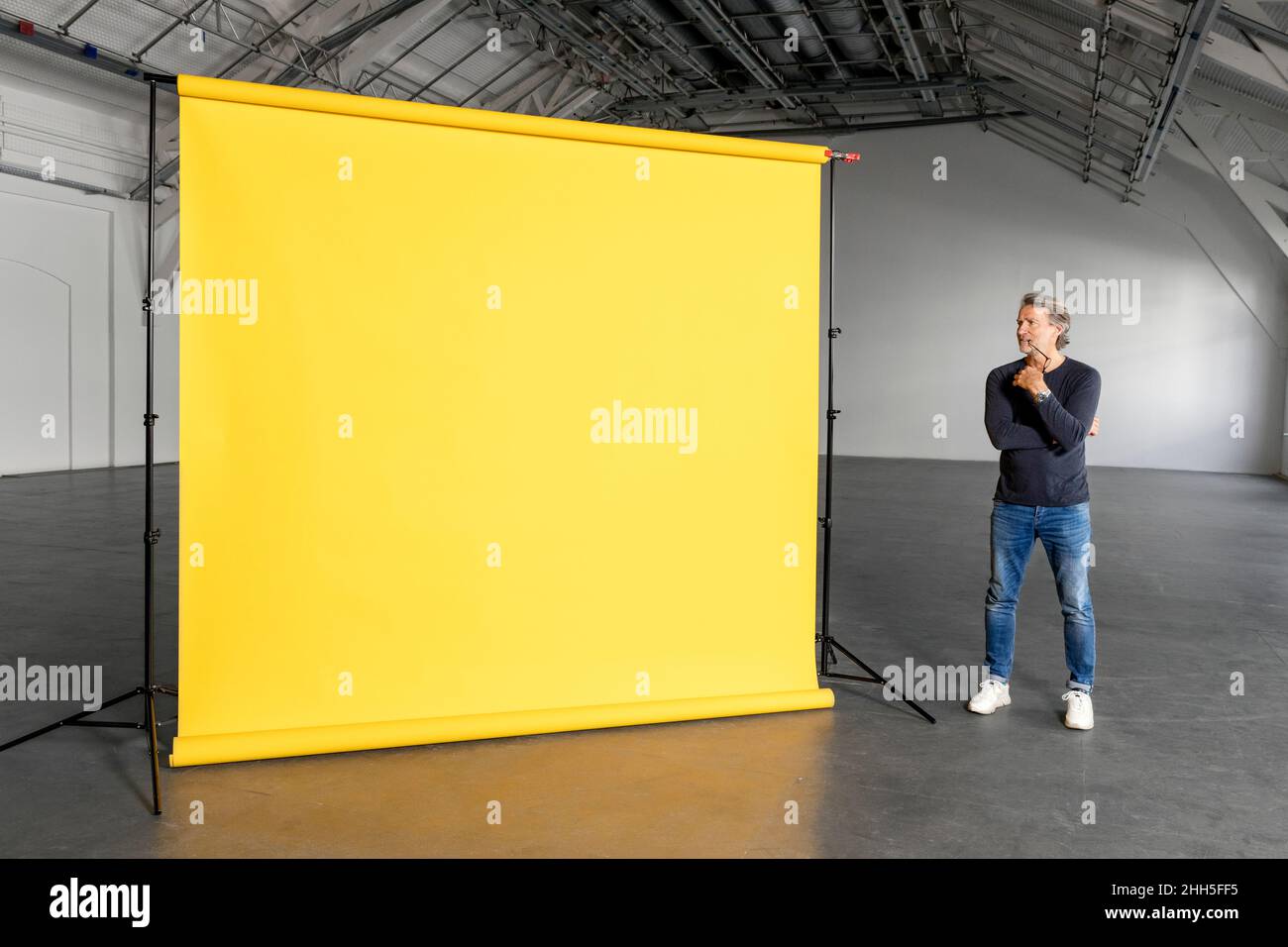 Thoughtful businessman looking at blank yellow backdrop in industial ...