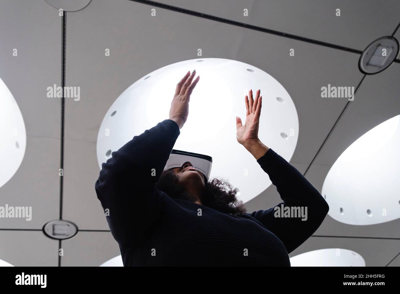 Woman wearing virtual reality simulator under illuminated ceiling Stock ...