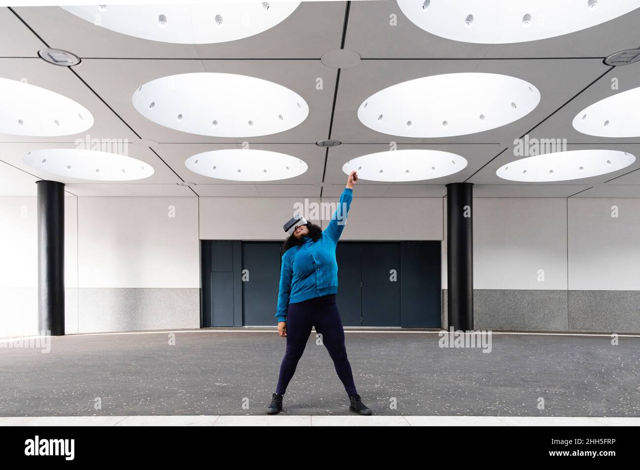 Woman raising hand wearing VR headset under illuminated ceiling Stock ...
