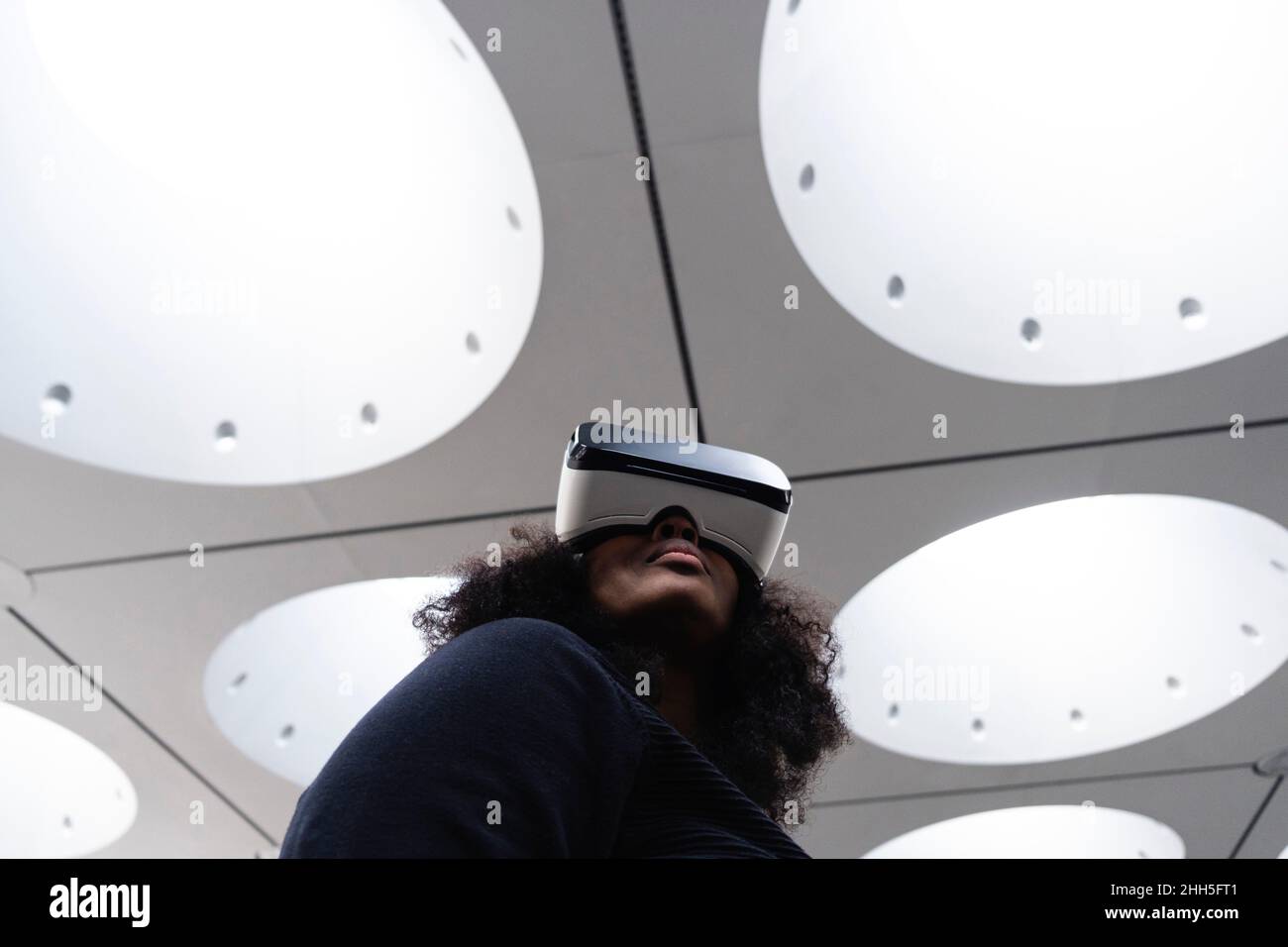 Woman wearing virtual reality simulator under illuminated ceiling Stock ...