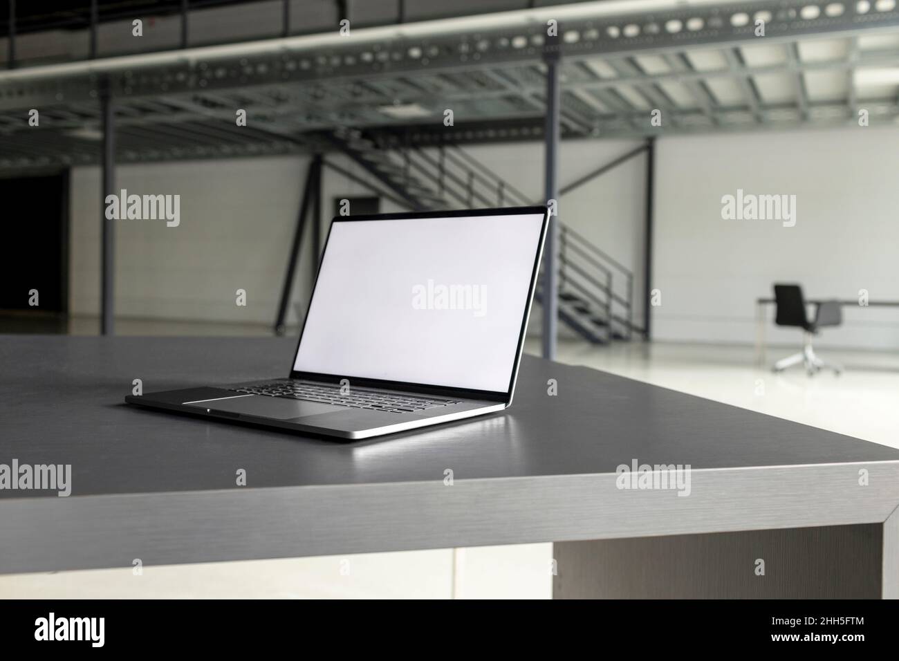 Laptop with blank screen at desk in industial hall Stock Photo - Alamy