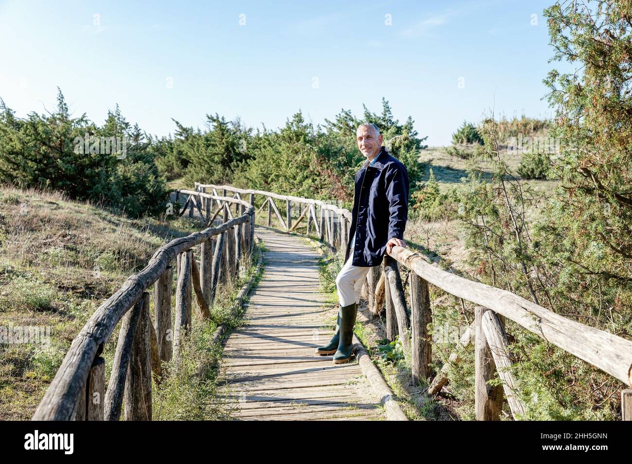 Man leaning on railing at wooden bridge Stock Photo - Alamy