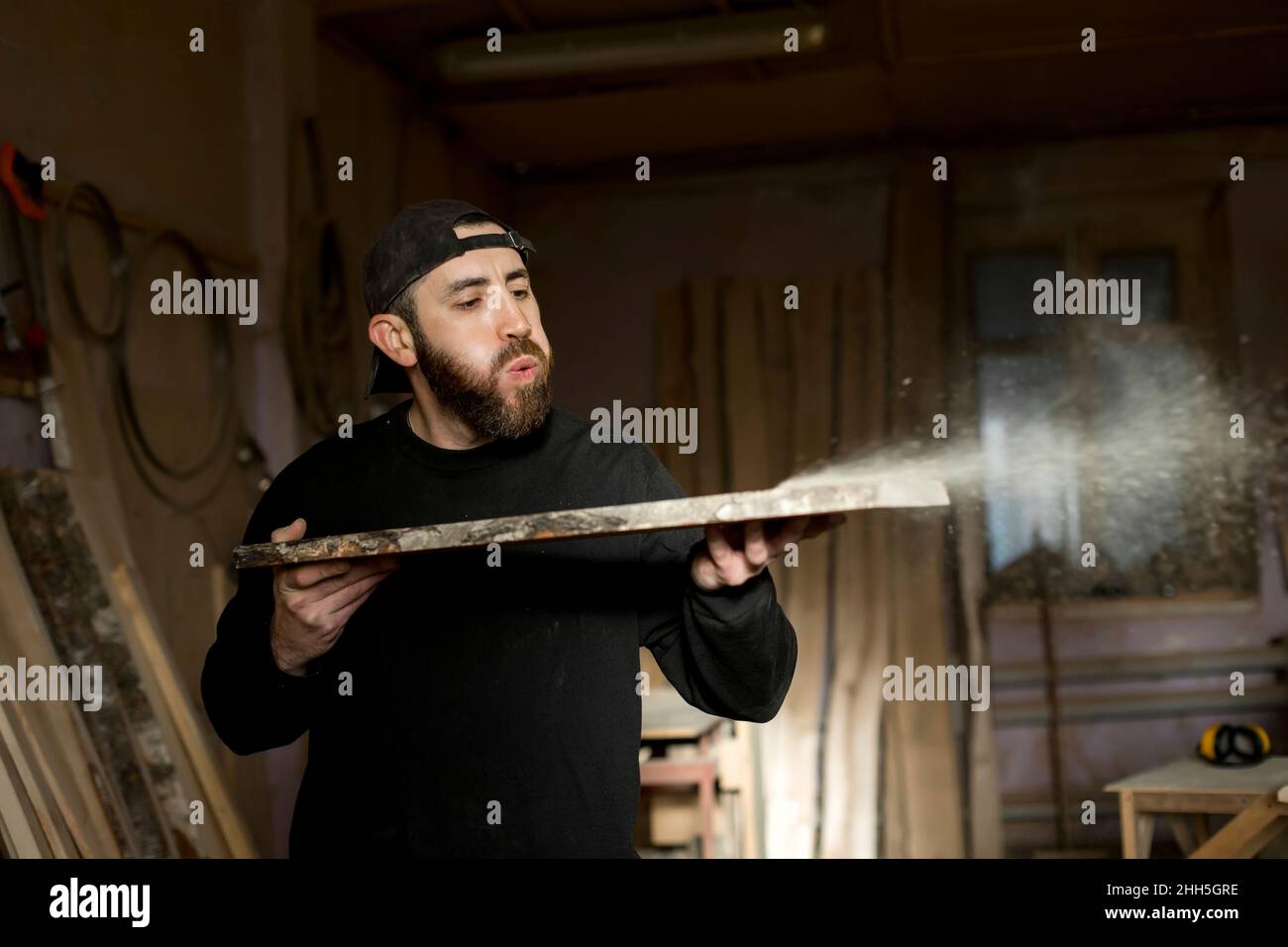 Carpenter blowing sawdust from plank at workshop Stock Photo - Alamy
