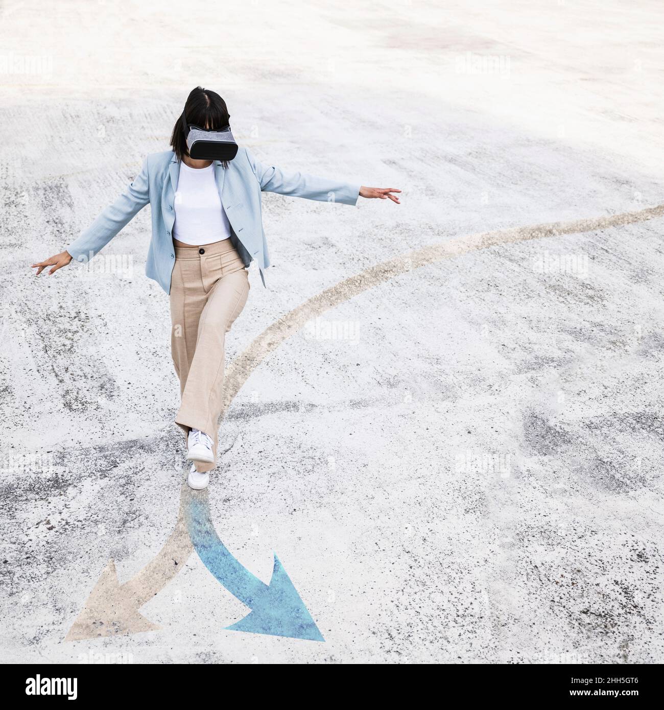 Teenage girl wearing virtual reality simulator walking on arrow symbol ...
