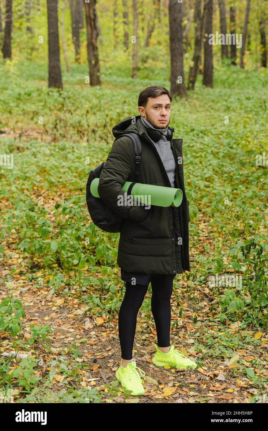 Athlete with backpack holding exercise mat in park Stock Photo - Alamy