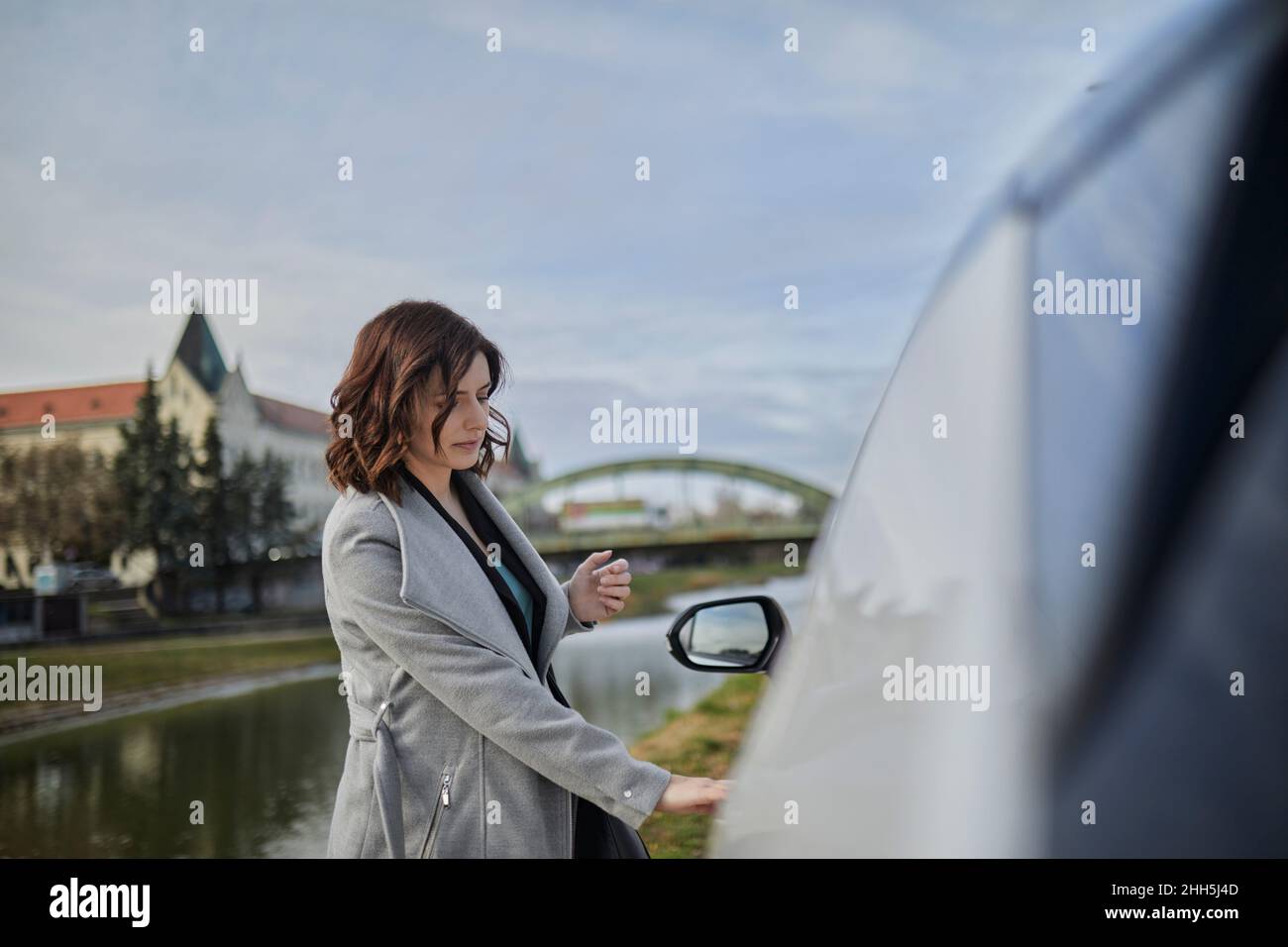 Woman in jacket opening door of electric car Stock Photo - Alamy