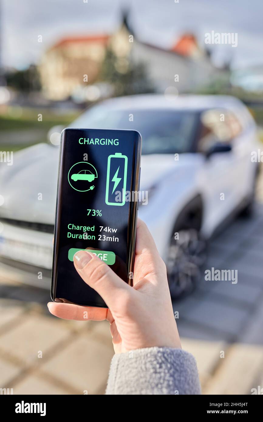 Woman checking electric car charging status through mobile phone Stock ...