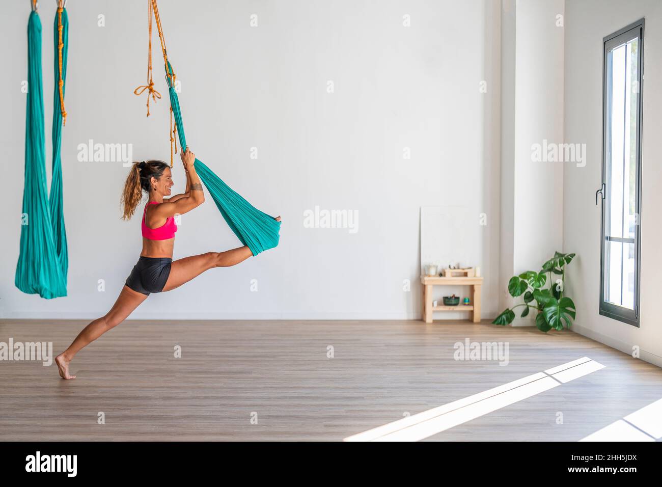 Flexible woman stretching on aerial silk in yoga studio Stock Photo - Alamy