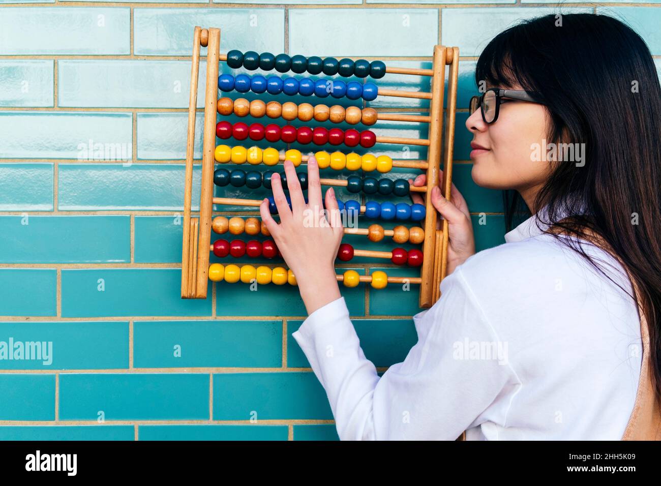 Young woman counting beads on abacus by brick wall Stock Photo - Alamy