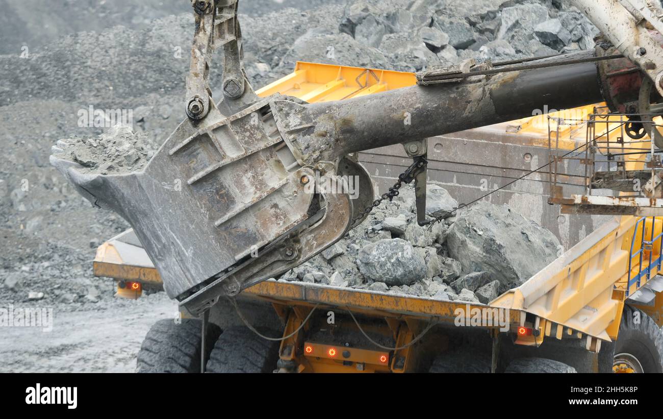 Close-up of excavator loading the dumper with ore in the quarry. Mining ...