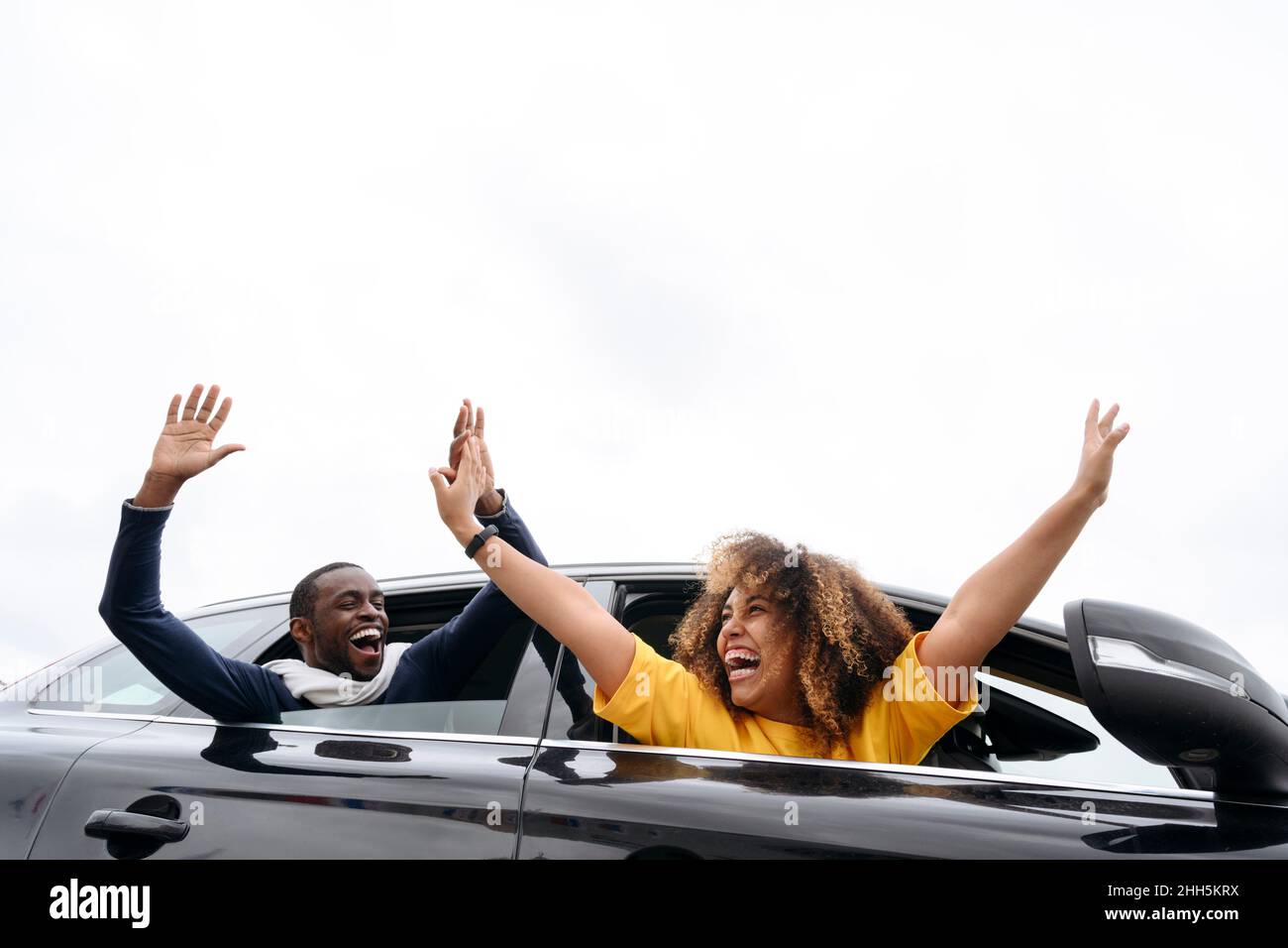 Happy friends leaning out of car windows on road trip Stock Photo - Alamy