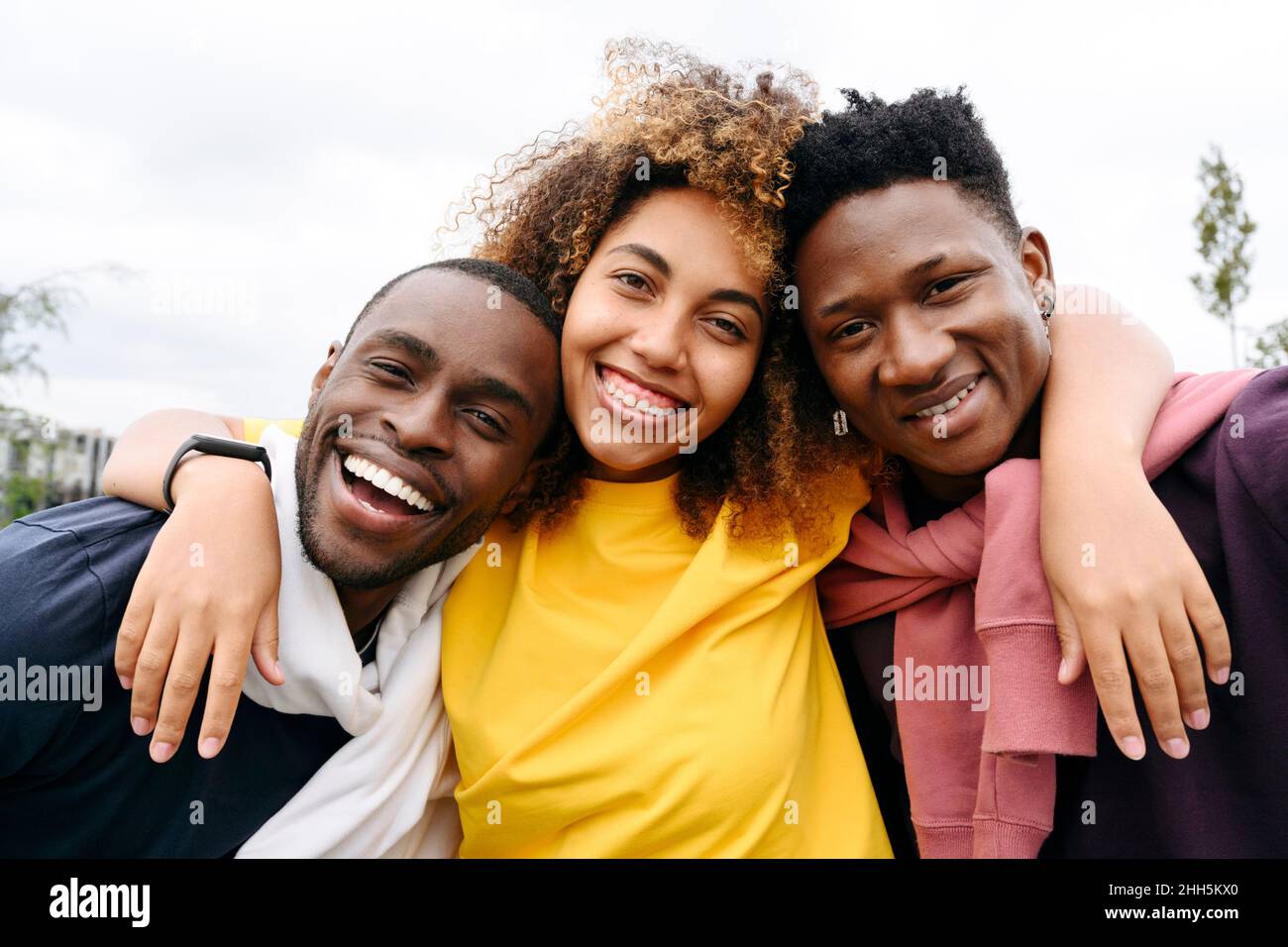 Happy woman with arms around friends outdoors Stock Photo - Alamy