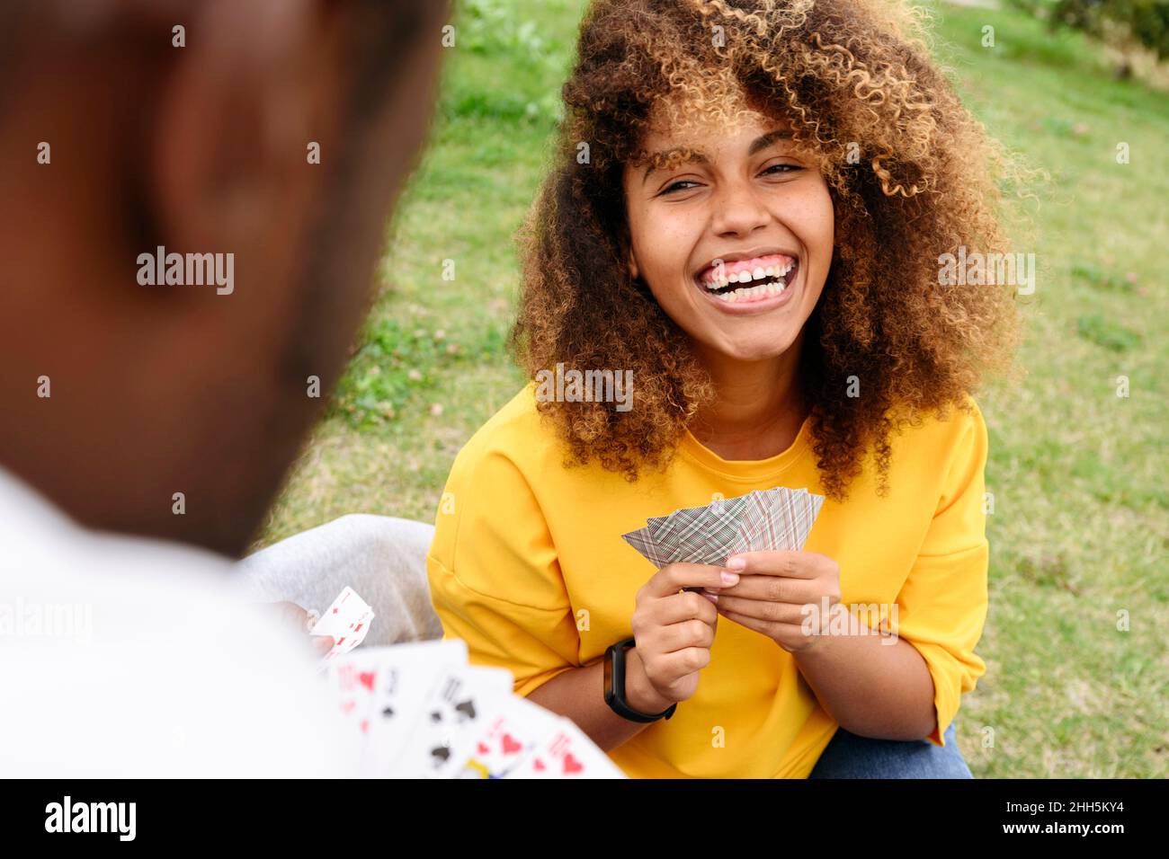 Woman laughing and playing cards with friend in park Stock Photo - Alamy