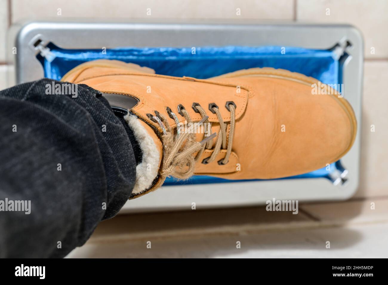 Device for automatic dressing of boot covers, a man in brown shoes puts ...