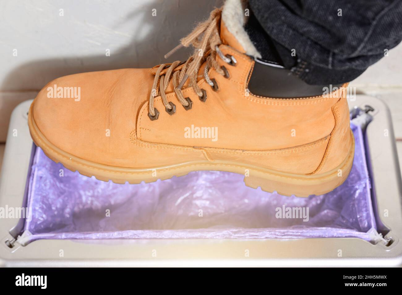 Device for automatic dressing of boot covers, a man in brown shoes puts ...