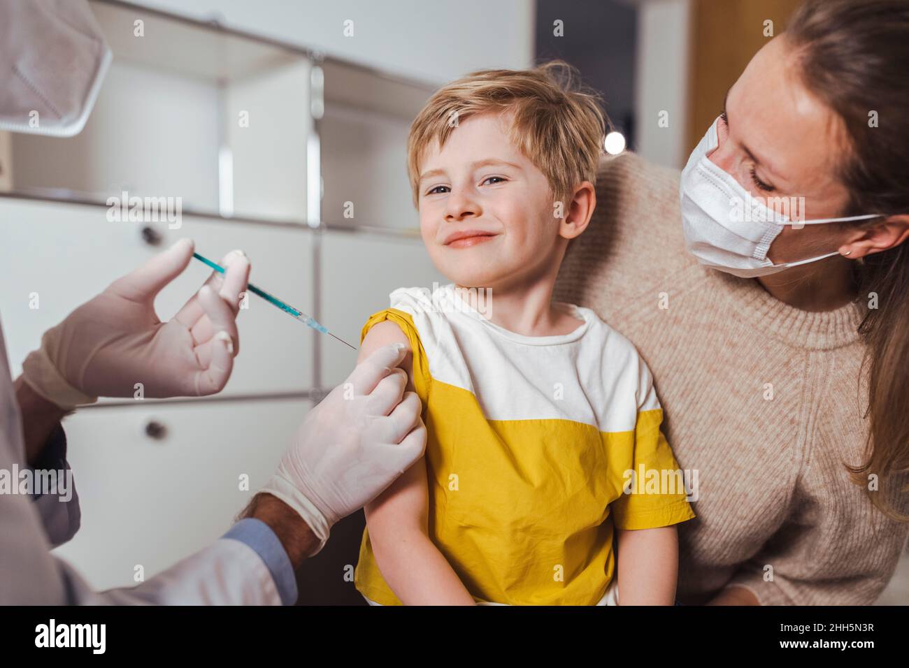 Smiling boy getting vaccine injection by doctor in center Stock Photo ...