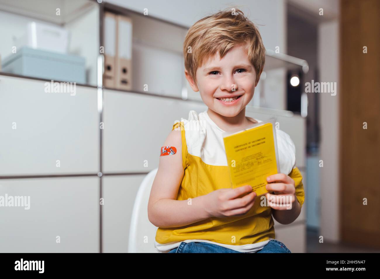 Happy boy holding immunization certificate at center Stock Photo - Alamy