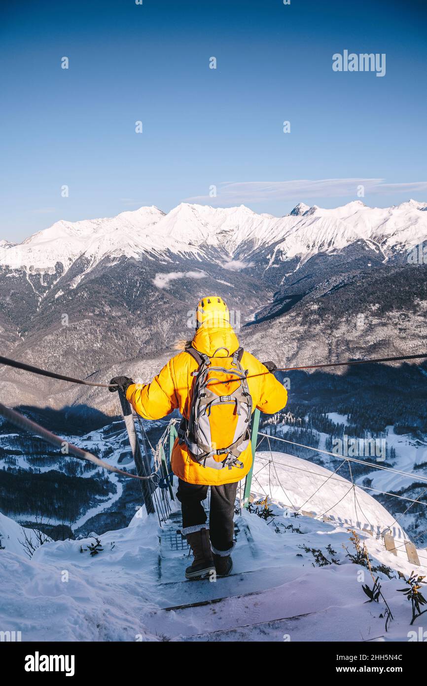 Man wearing yellow jacket hiking downhill mountains Stock Photo - Alamy