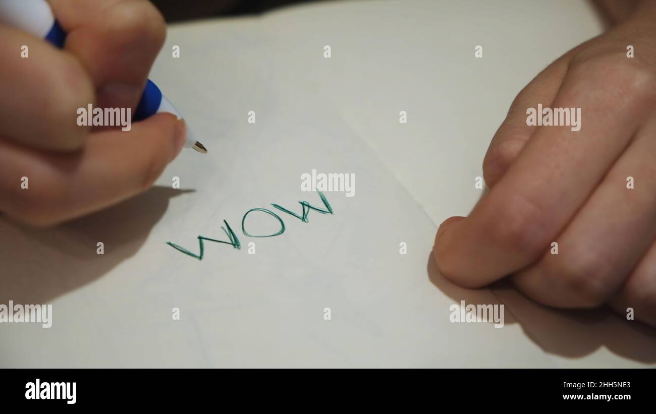 Close up of hand writing words on white paper with a pen. Child is ...